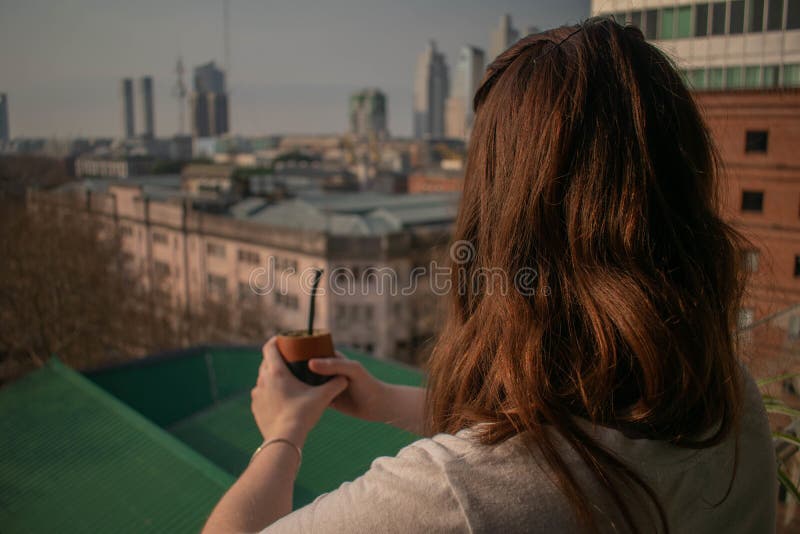Back View of a Brunette Female Looking Over the City from a Balcony ...