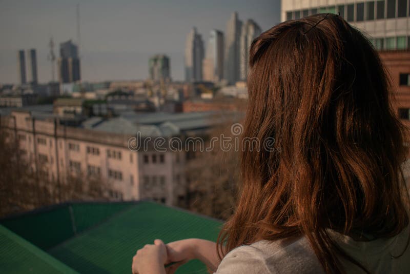 Back View of a Brunette Female Looking Over the City from a Balcony ...