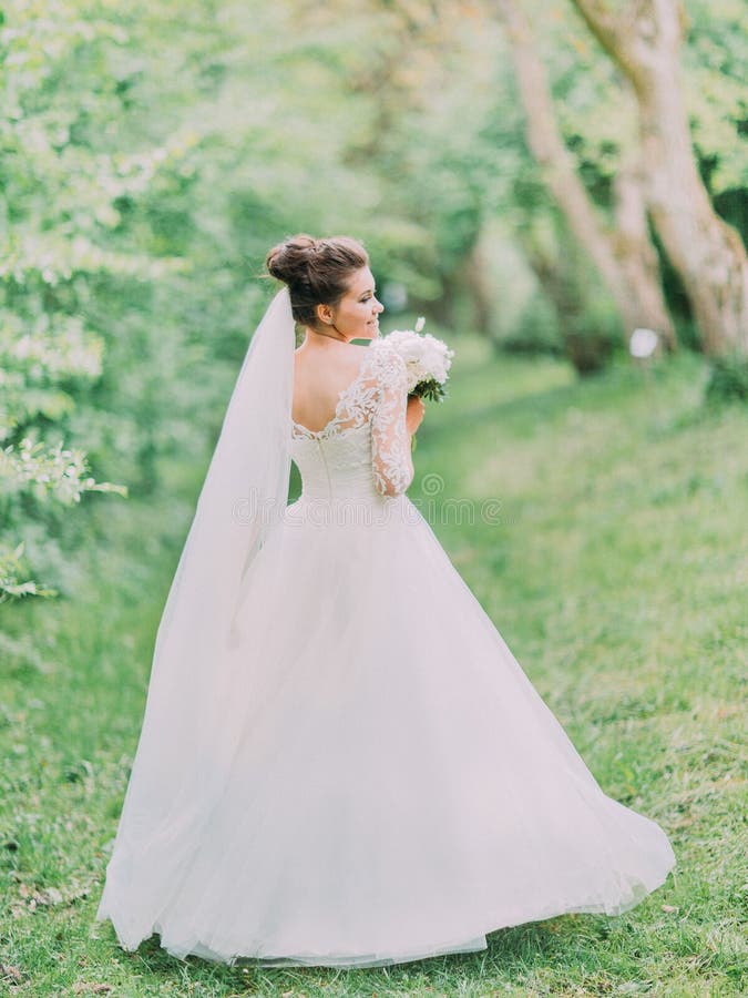 The Back View of the Charming Bride Holding the Wedding Bouquet during ...