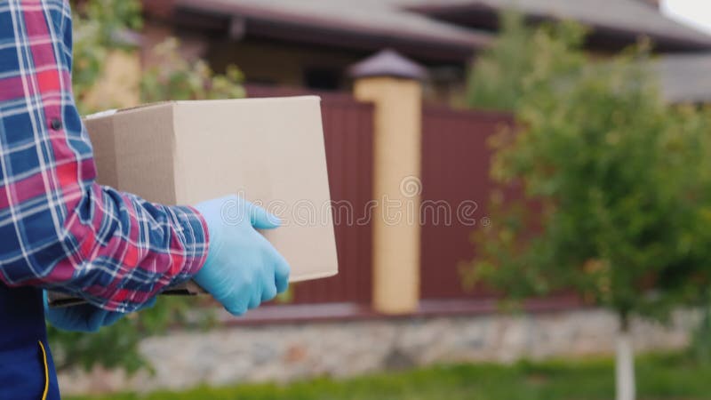 A Courier with a Parcel of Hands Walks Along the Street. he S Wearing ...