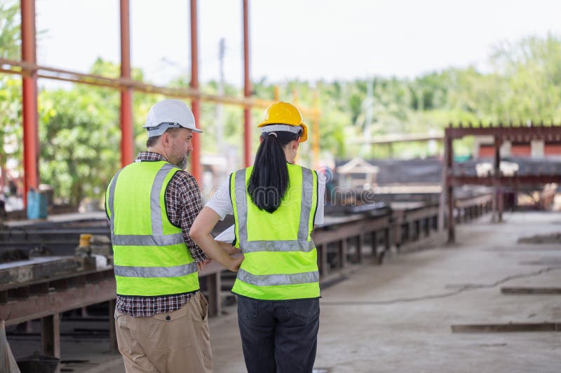 Back View of Engineer and Foreman Worker Team with Blueprints Checking ...
