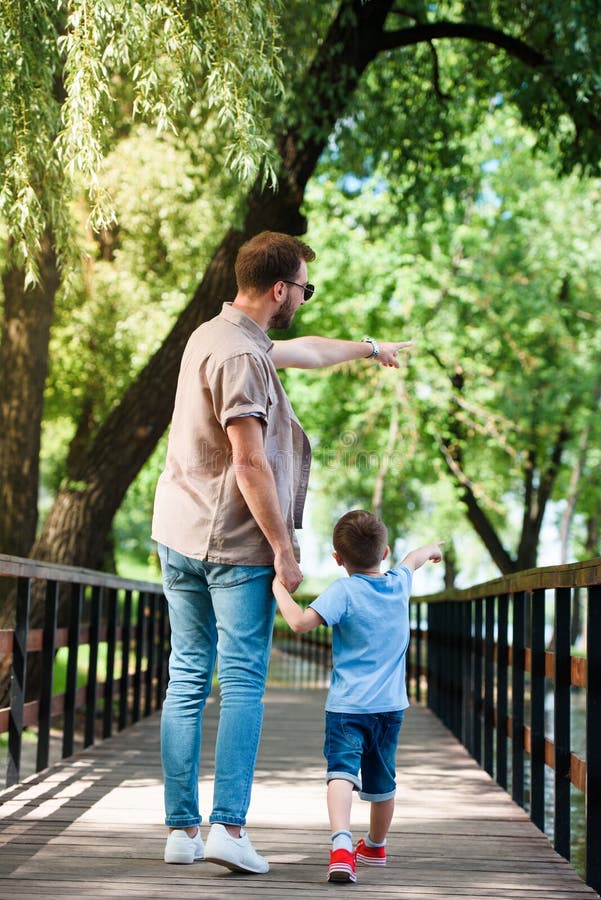 Back View of Father and Son Pointing on Something on Bridge Stock Photo ...