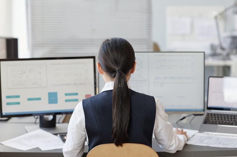 Back View of Female Engineer Using Computer with Blueprints on Screens ...