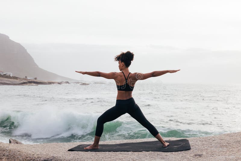 Back View of Female Practicing Yoga in Warrior Pose by the Ocean at Bay ...