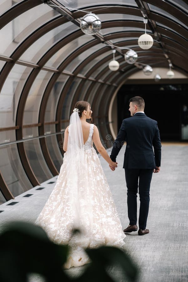 Back View of Groom and Bride Walk in the Big Hall with Windows. Elegant ...