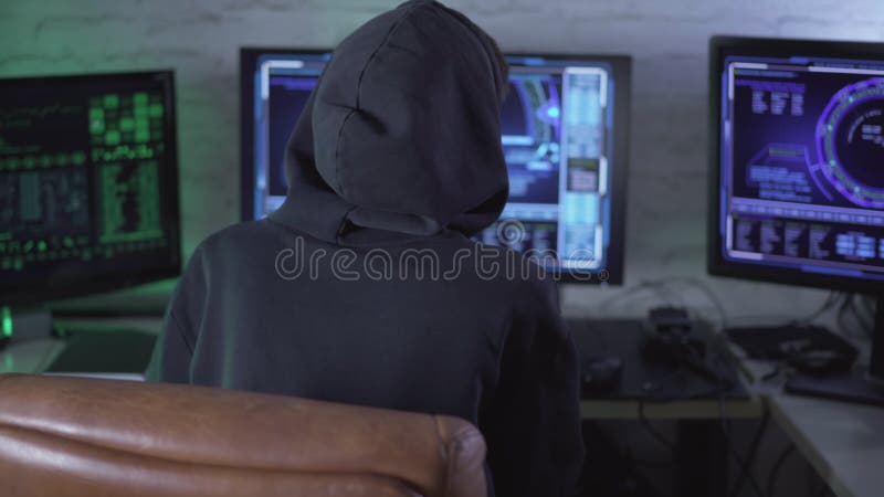 Back View of Hacker in Hood Using Multiple Computers for Cyber Attack. Unrecognizable Programmer ...