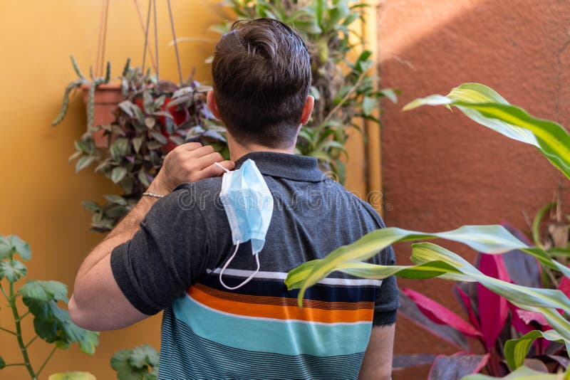 Back View of a Male Holding a Protective Face Mask Behind His Back ...