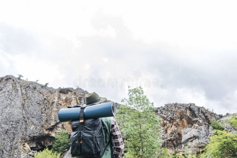 Back View of a Man with Backpack and Hat Hiking in the Mountains at ...