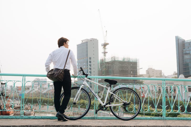 Back View Man with a Bicycle Stands on the Bridge Looking at the City ...