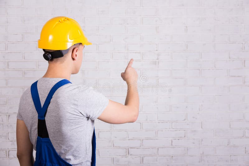 Back View of Man in Blue Builder Uniform Pointing at White Wall Stock ...