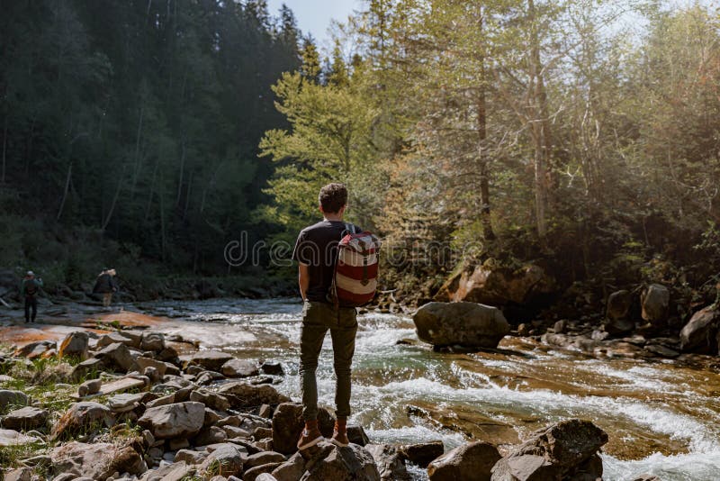 Back View on Man Hiker with Backpack Standing at River with Rocks and ...