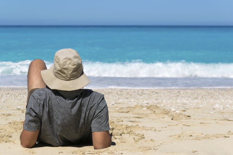 Back View of a Man Leaning Back on His Elbows on the Beach and Looking ...