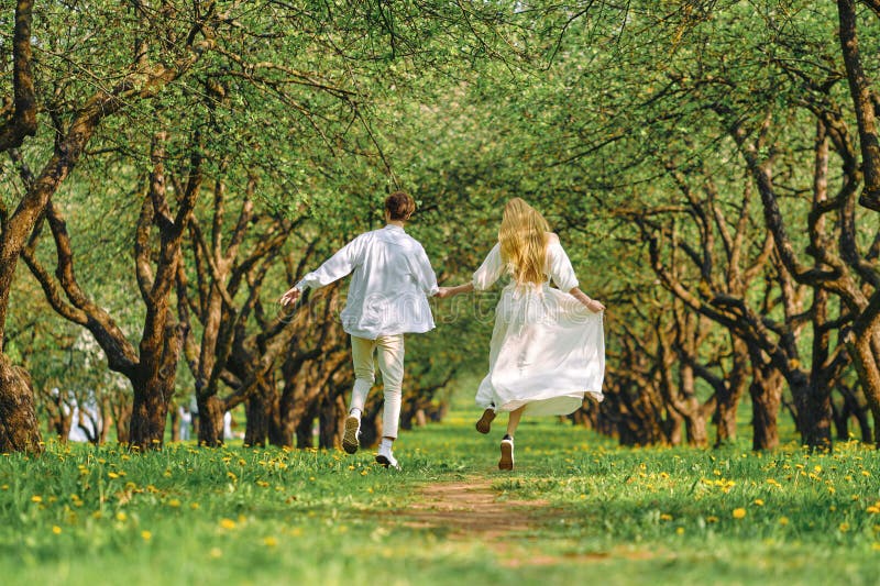 Back View of Newlyweds Hold Hands and Run Along Trail in the Park Stock ...