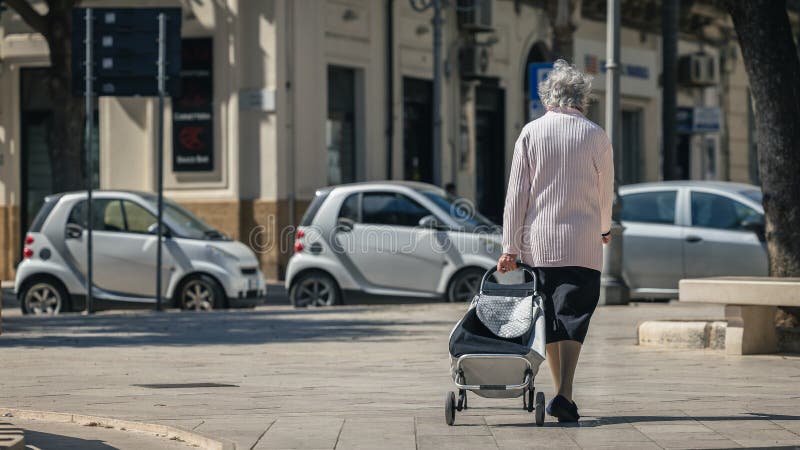 Back View of Older Lady Pulling a Shopping Trolley or Cart Away from ...