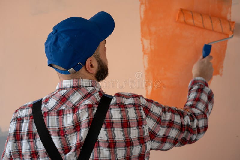 Back View of Painter with Blue Cap Painting Orange Spot on Wall with ...