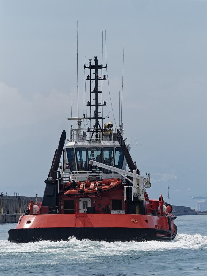 Back View of a Powerful Tugboat Moving Fast Next To Breakwater To the ...