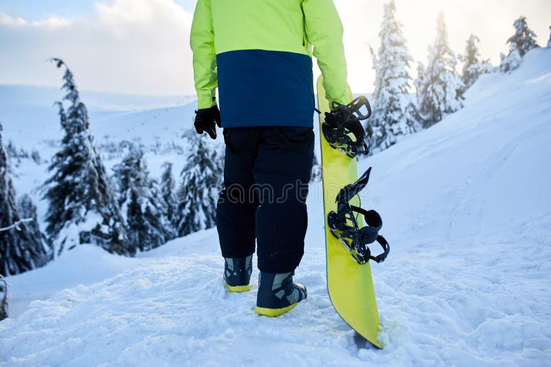 Back View of Snowboarder Climbing with His Board on the Mount for ...