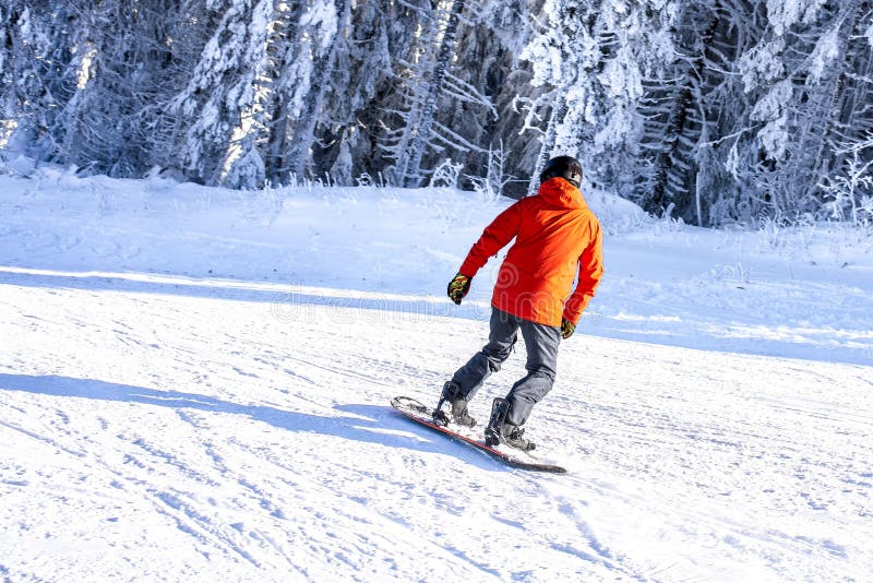 Back View of a Snowboarder Riding Down the Ski Slope in the Mountains ...
