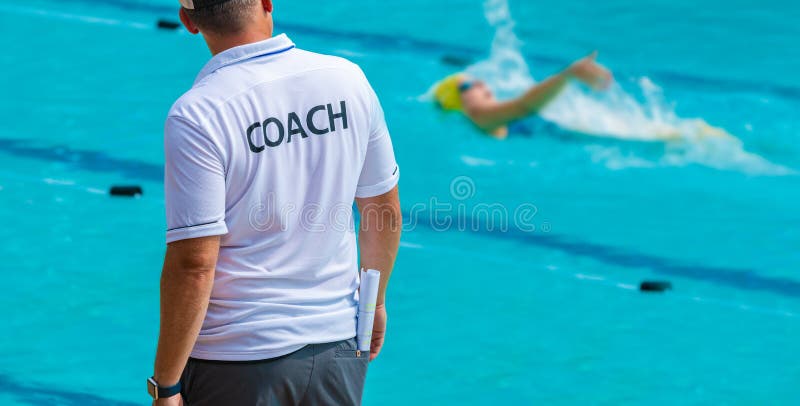 Male Swimming Coach Standing By The Swimming Pool In The Rain Wa