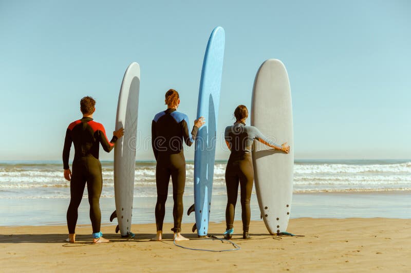 Back View of Surfers in Wetsuits Standing with Surfboards and Looking ...
