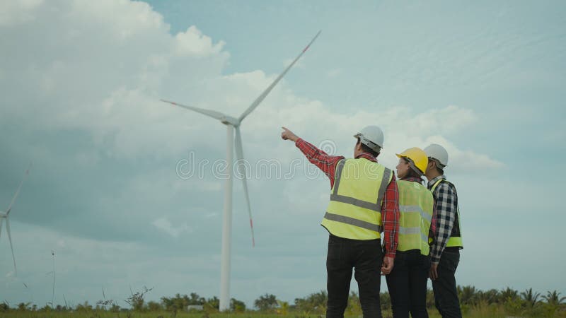 Back View of Three Engineers Discussing and Progress Check Wind Turbine ...