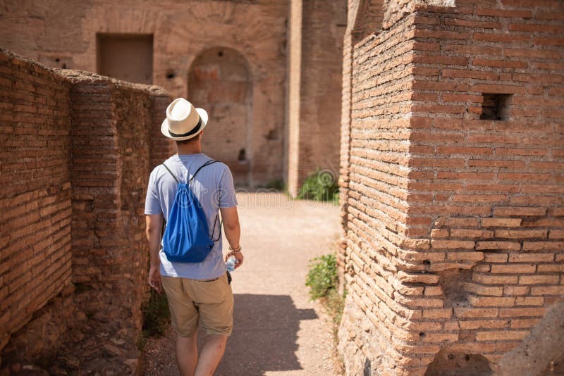 Back View of a Tourist with a Blue Backpack and Straw Beige Hat Walking ...