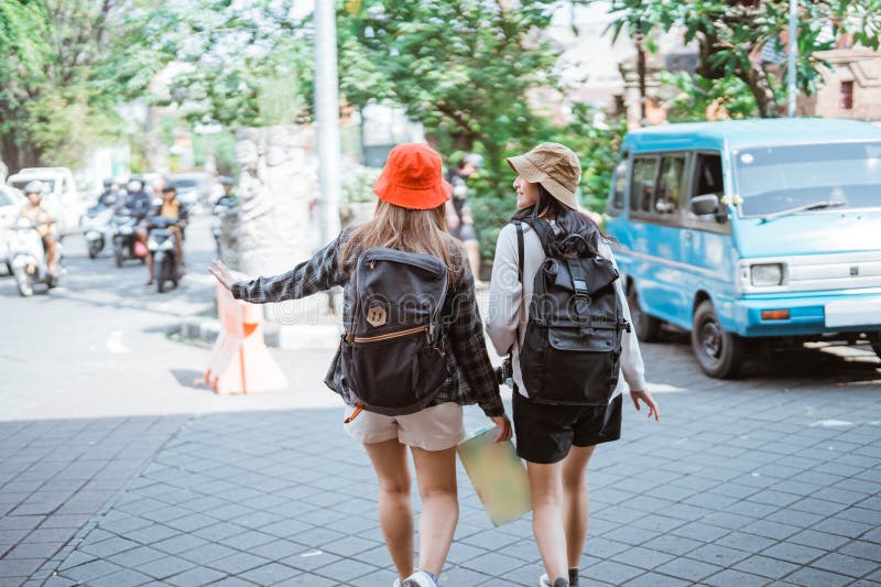 Back View of Two Backpacker Girls Walking Carrying a Map while ...