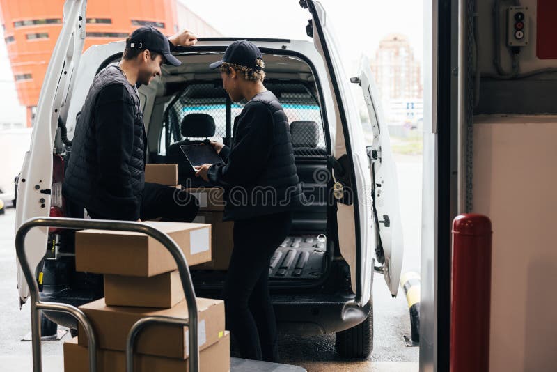 Back View of Two Delivery People Checking Information on a Digital ...