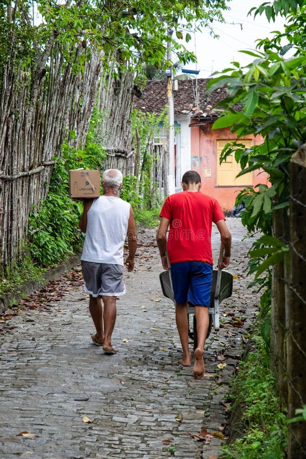 Back View of Two Men Carrying Goods To the Store through the Streets of ... Back View of Two Men Carrying Goods To the Store through the Streets of ...