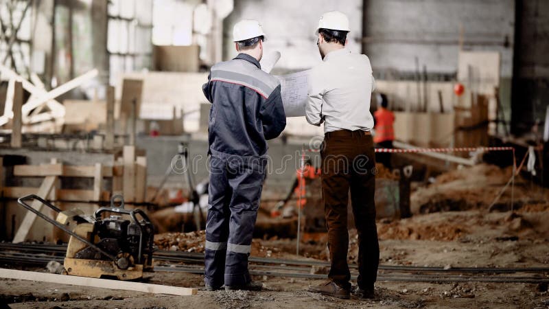 Back View of Two Men Standing Together in Construction Area and Looking ...