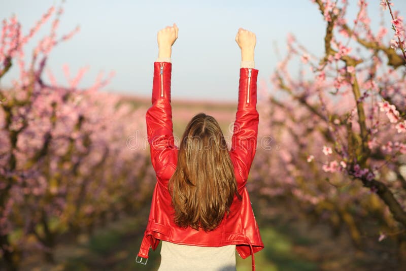 Back View of a Woman in Red Celebrating in a Flowered Field Stock Photo ...