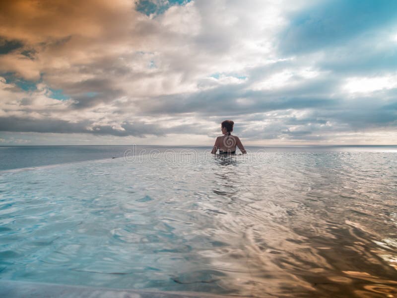 Back View of a Woman Standing in an Infinity Pool Stock Photo - Image ...