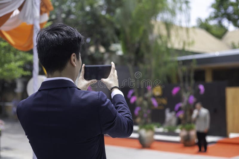 Back View of Young Businessman Taking Photos at Outdoors Event W ...