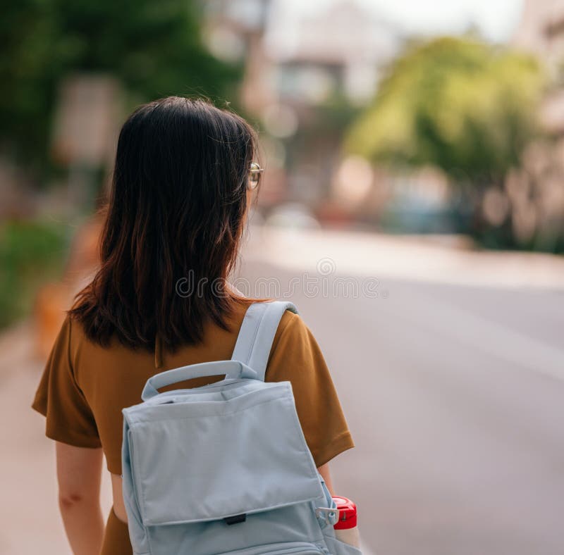 Back View of a Young Female with a Backpack Walking on a Sidewalk Stock ...