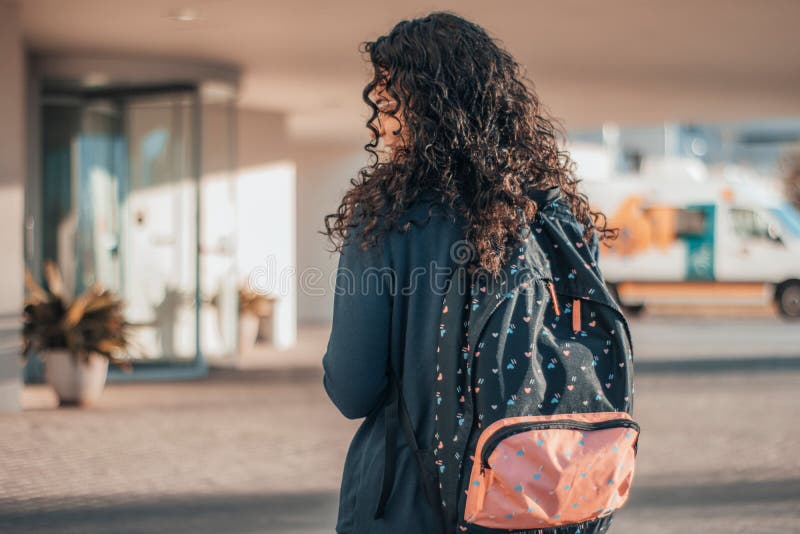 Back View of a Young Female with Curly Hair and a Backpack Standing on ...