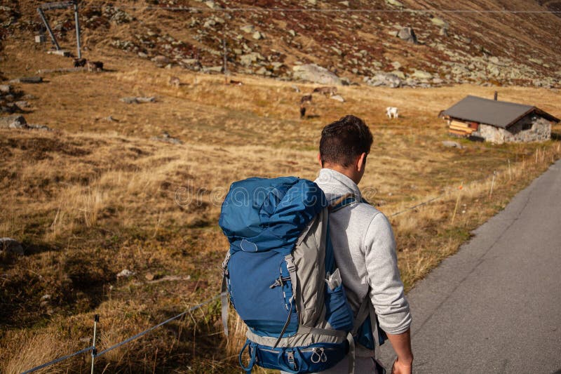 Back View of Young Man with Backpack Standing on the Road in Mountains ...