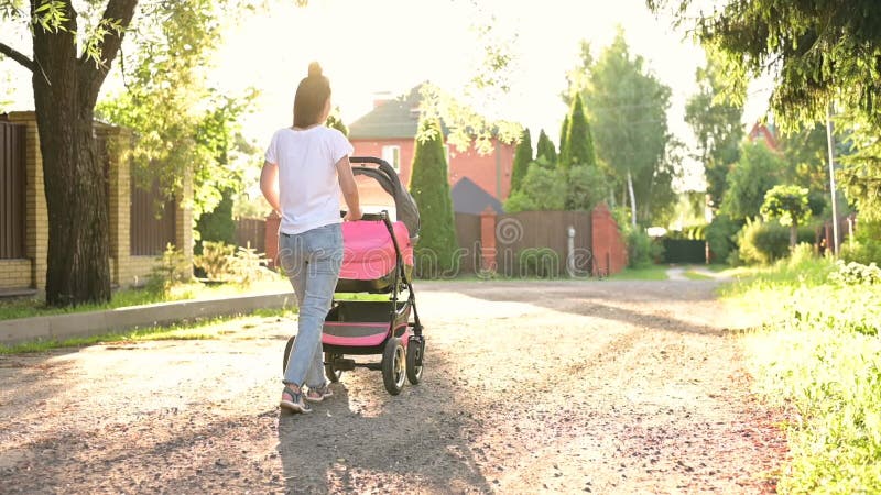 Back View of a Young Mother Walking with a Stroller on a Sunny Evening ...