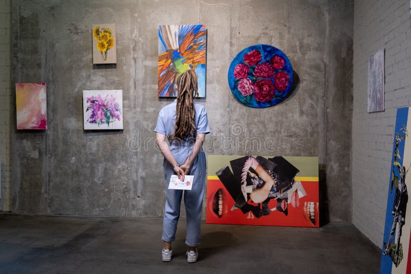 Back View of Young Woman Standing in Front of Wall with Artwork ...