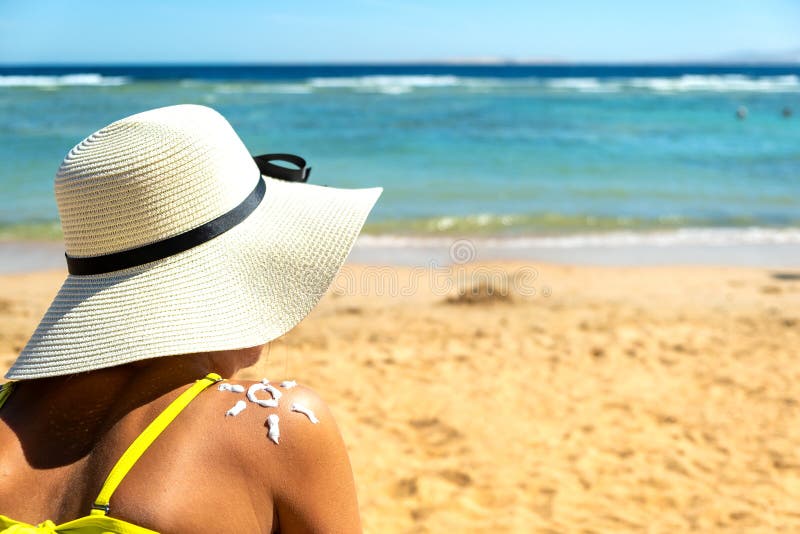 Back View Of Young Woman Tanning At The Beach With Sunscreen Cream In