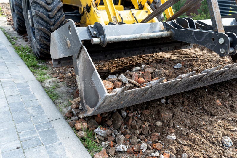 A Backhoe Loader Carries and Levels Rubble on a Dirt Road. Stock Photo ...