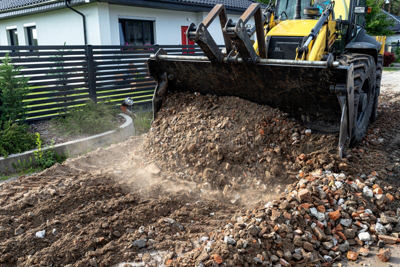 A Backhoe Loader Carries and Levels Rubble on a Dirt Road. Stock Photo ...