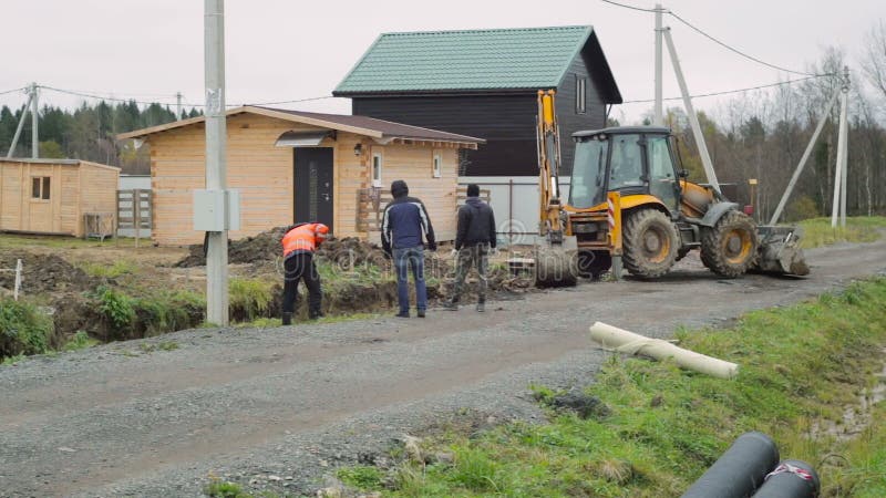 Backhoe Loader Digging Soil. Workers are Digging with Shovels Stock ...