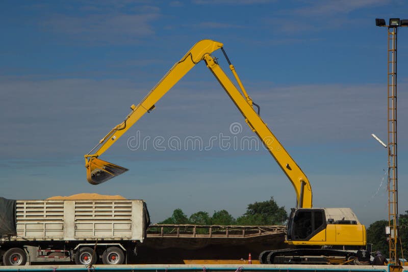 Backhoe Loading Ground into a Dump Truck on Construction Site. Birds ...