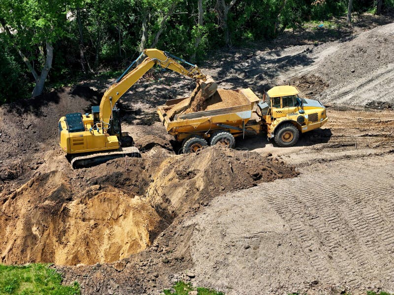 Backhoe Loading a Large Dump Truck at a Construction Site Stock Image ...