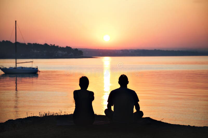 Backlit Couple Admiring the Sunrise Over the Sea Stock Image - Image of ...
