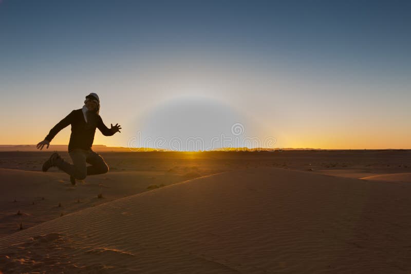 A Backlit Man Jumps Happily in the Erg Chebbi Desert at Dawn Stock ...