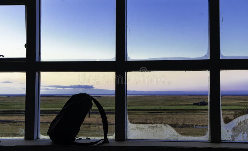 A Backpack is Sitting on a Window Sill. the Sky is Blue and the Sun is ...