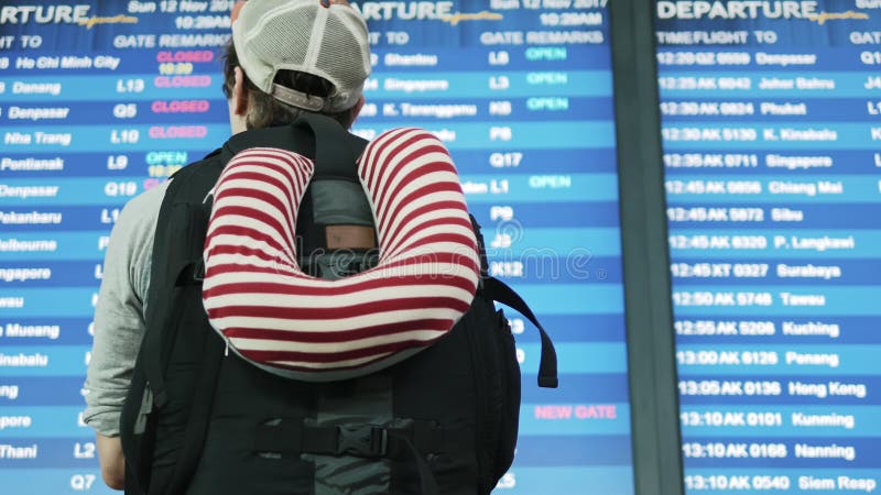 Backpacker Checking Flight Information on Digital Schedule Display in ...