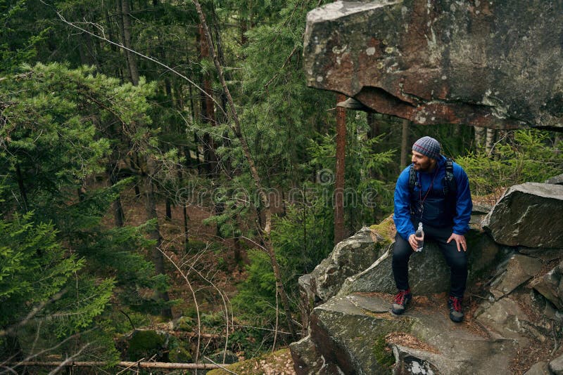 Backpacker Sitting Under Rock with Water Bottle Stock Photo - Image of ...