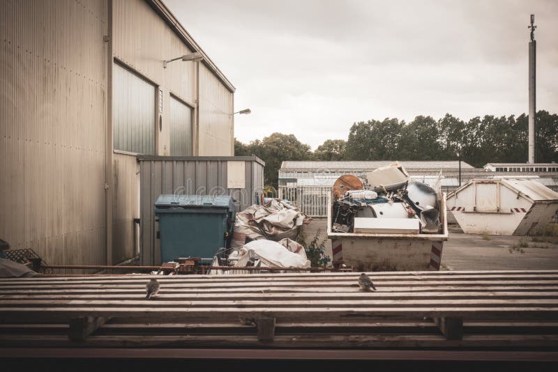 In a Backyard There are Garbage Containers and a White Container with ...